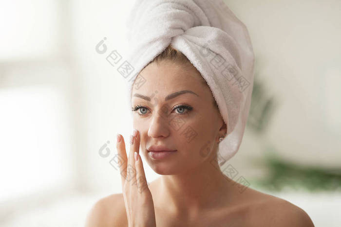年轻的妇女与完美的皮肤在她的脸上涂抹保湿 包图企业站