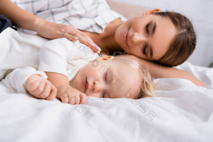 浅层快乐女人紧闭双眼触摸熟睡的儿子模糊的图片-包图网企业站