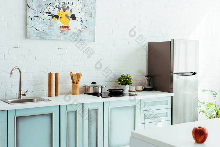 宽敞的明亮厨房桌上有厨具和红苹果图片-包图网企业站