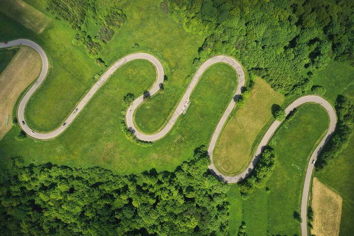 绿林间蜿蜒道路的空中无人驾驶图像-包图企业站
