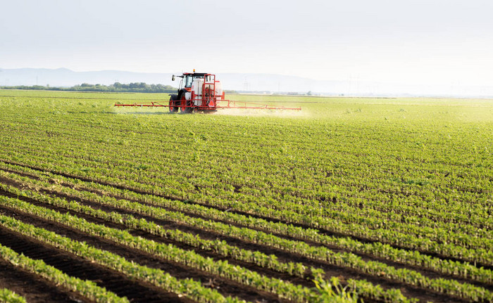 大豆田喷洒杀虫剂的拖拉机图片-包图网企业站