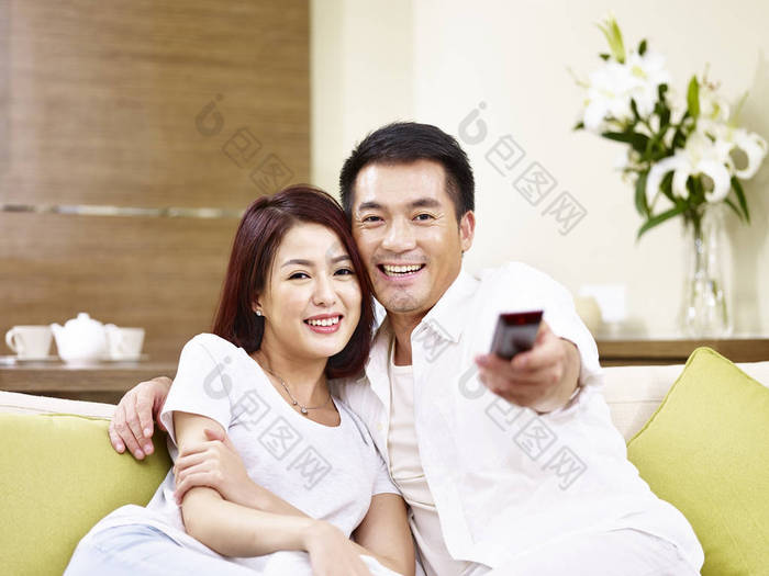 亚洲夫妇在家看电视 包图企业站