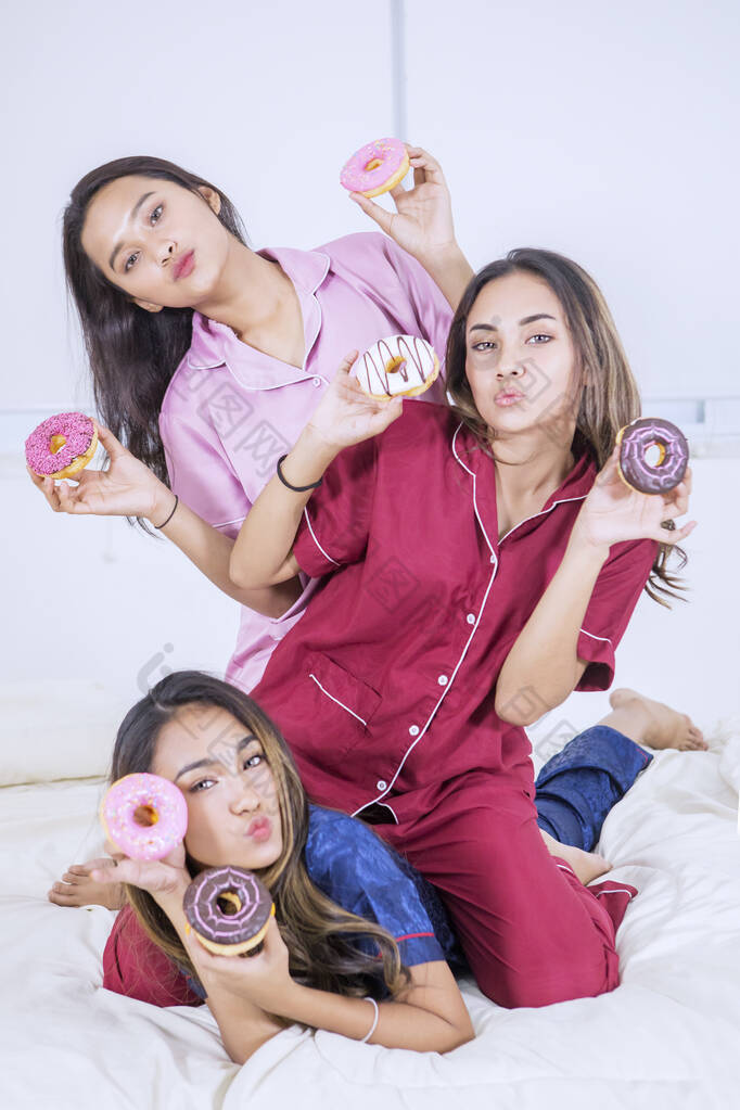 漂亮的少女在床上和甜甜圈玩乐图片 包图网企业站