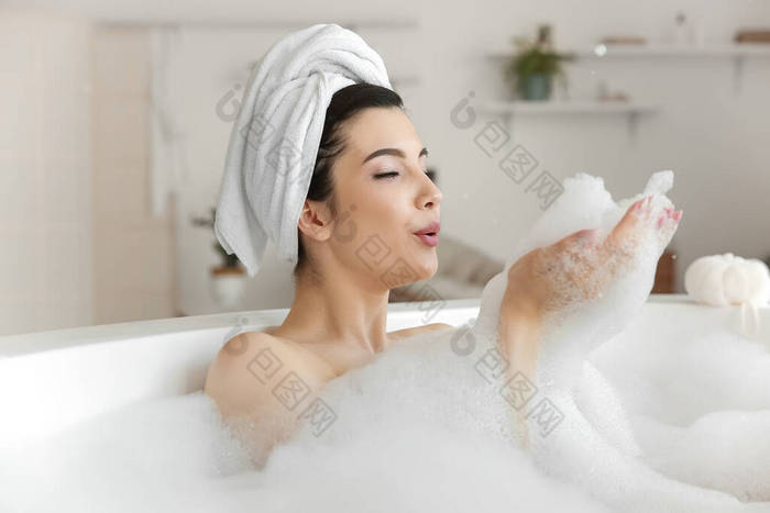 松懈的年轻女子在浴缸里吹泡泡图片 包图网企业站