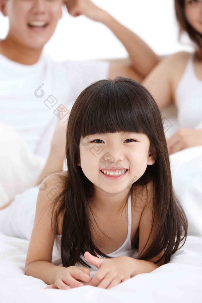 可爱的小女孩和父母在卧室的床上 包图企业站