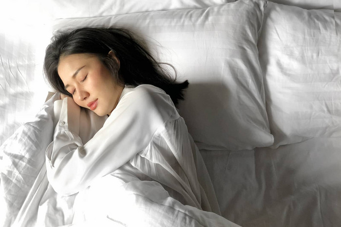 美丽的亚洲女人睡觉床上白色被子 包图企业站